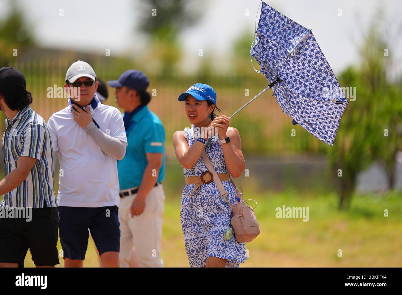 Jodi Nguyen has the wind take her umbrella as she walks in the gallery ...