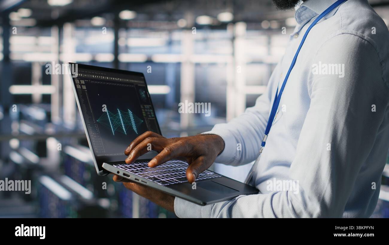 Engineer and colleague in data center reviewing large language model visualizations on laptop ...