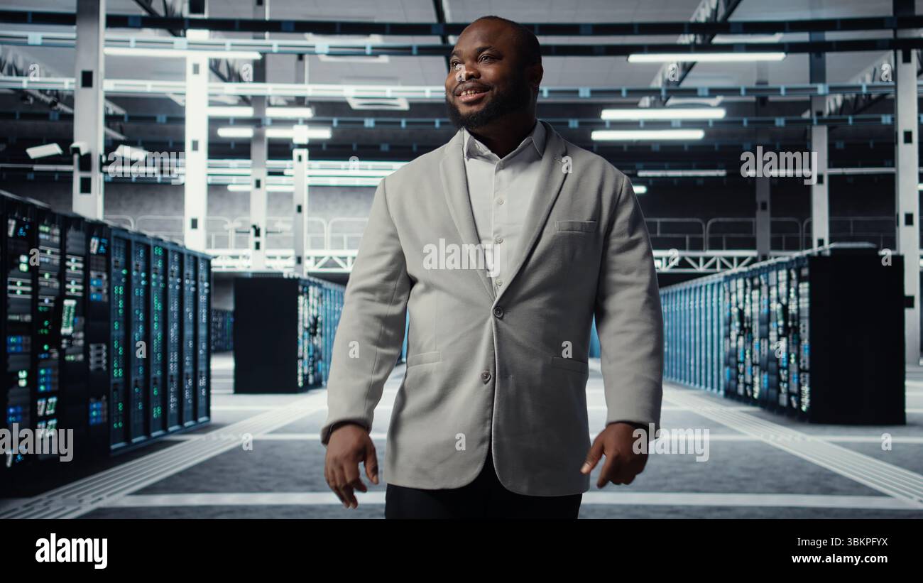 Smiling employee walking in high tech data center with machines ...