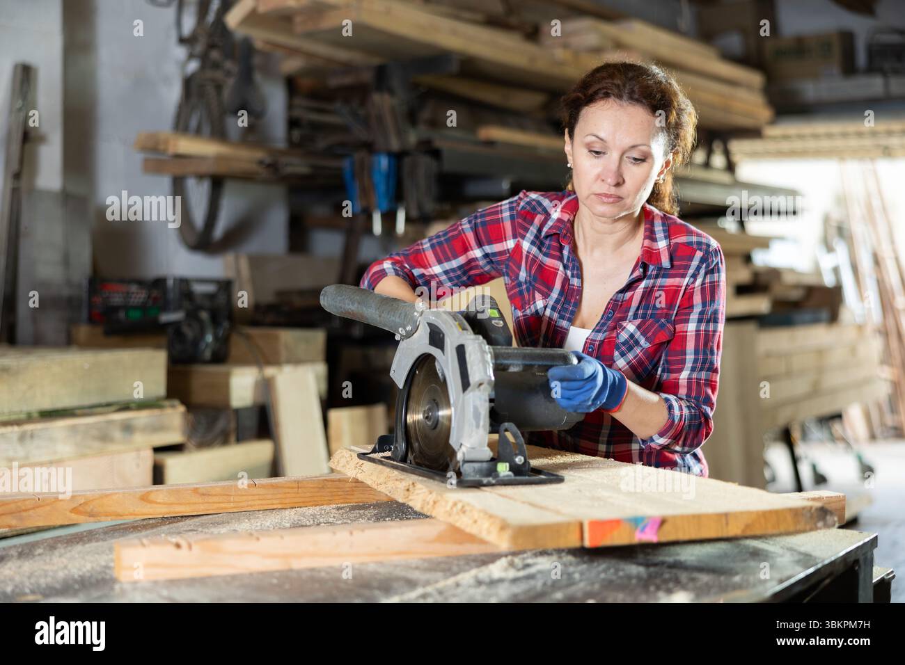 Working at sawmill - woman saws wooden board using circular saw Stock ...