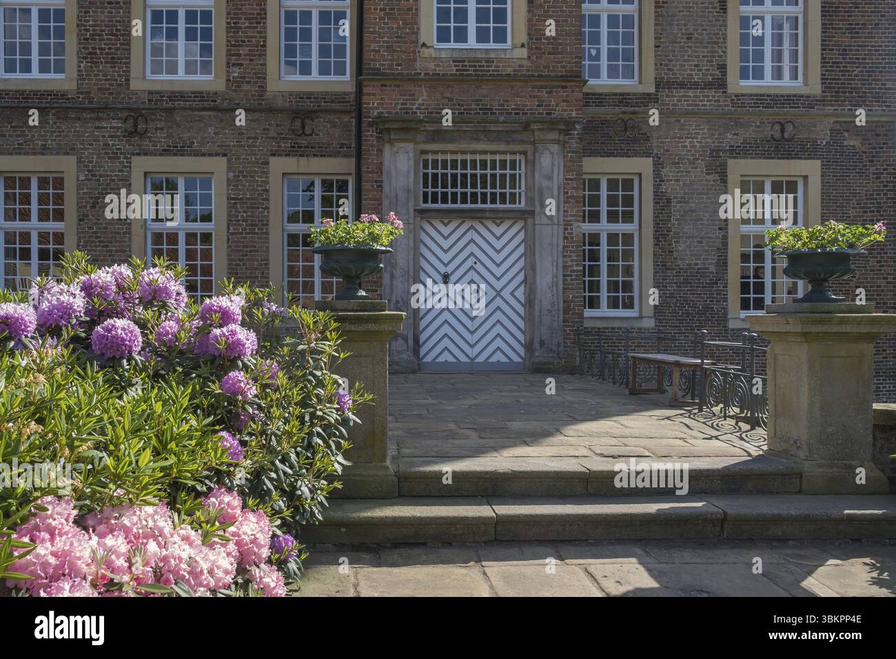An elegant entrance to a historic brick building with flowering plants ...