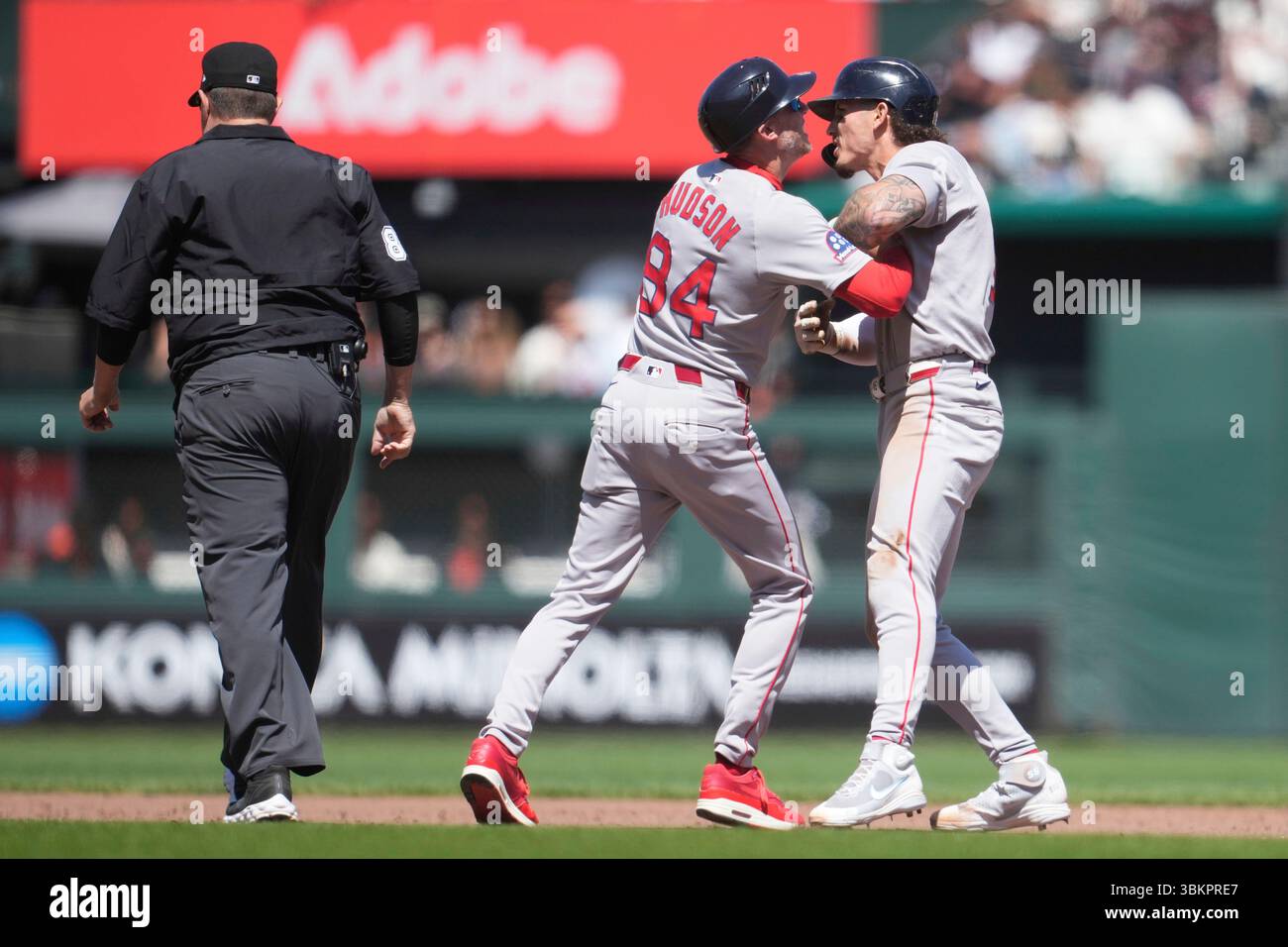 Boston Red Sox' Jarren Duran, right, is held back by third base coach ...