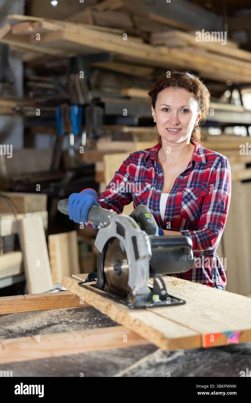 Working at sawmill - woman saws wooden board using circular saw Stock ...