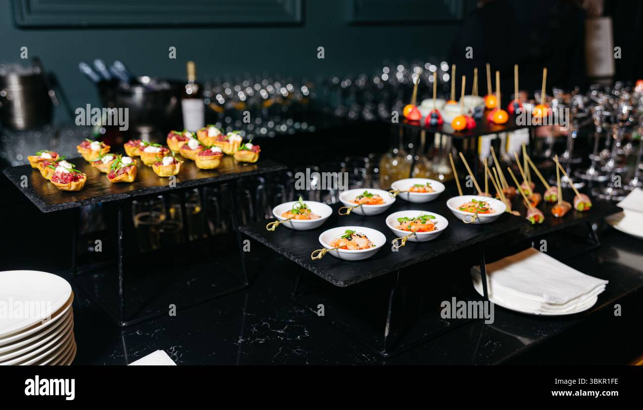Variety of stylish gourmet appetizers arranged on a black buffet table ...