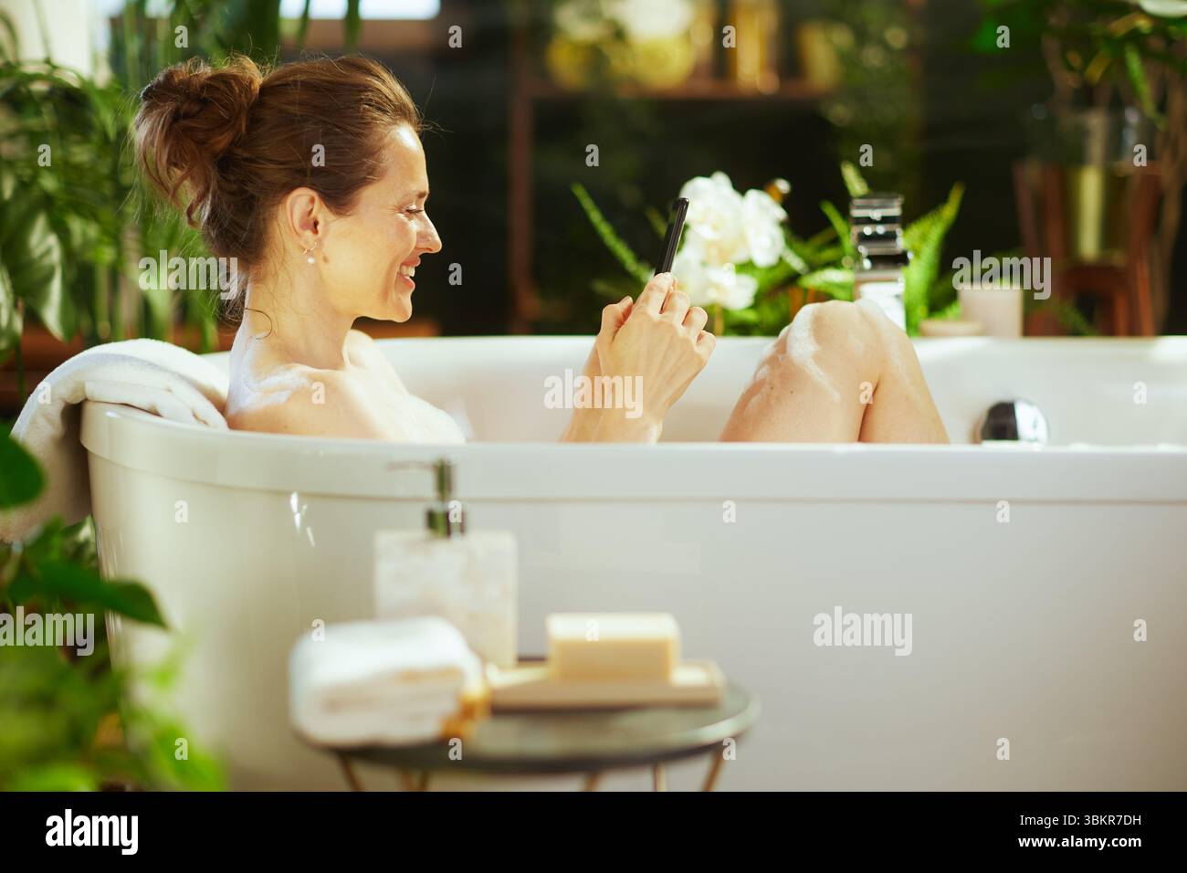 A contented middle-aged woman, hair in a bun, relaxes in a luxurious ...
