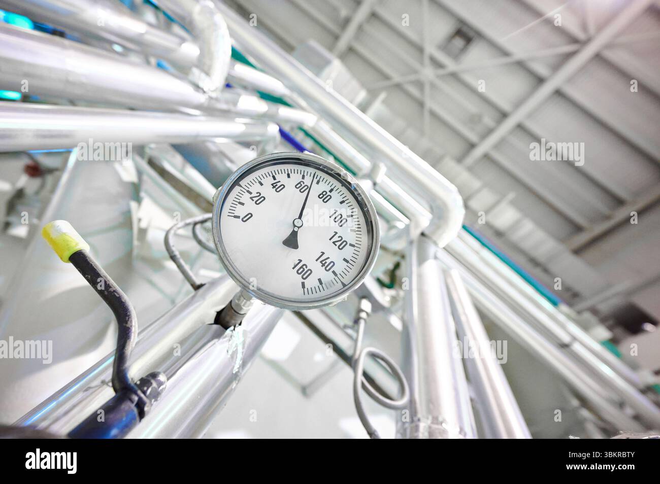 Round dial thermometer measures temperature in industrial piping system ...