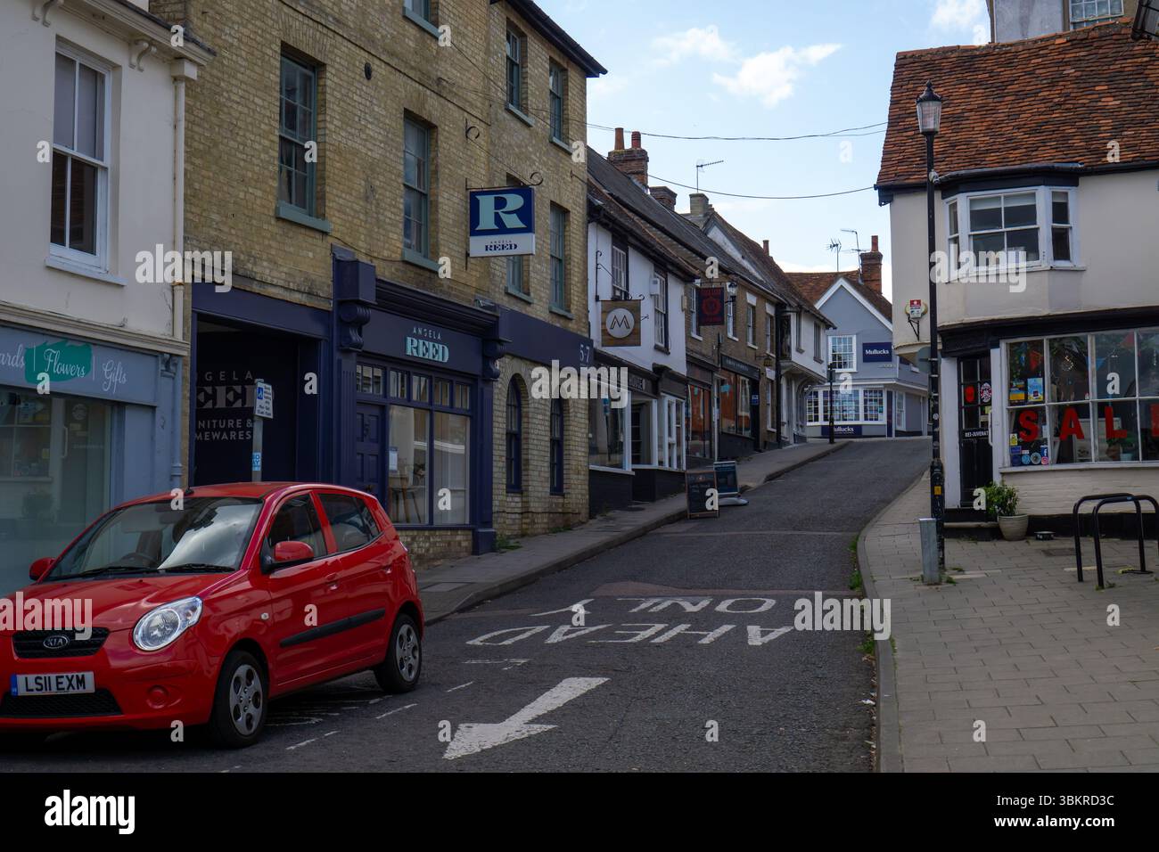 A charming street scene in Saffron Walden, Essex, England, featuring a red car parked on a ...