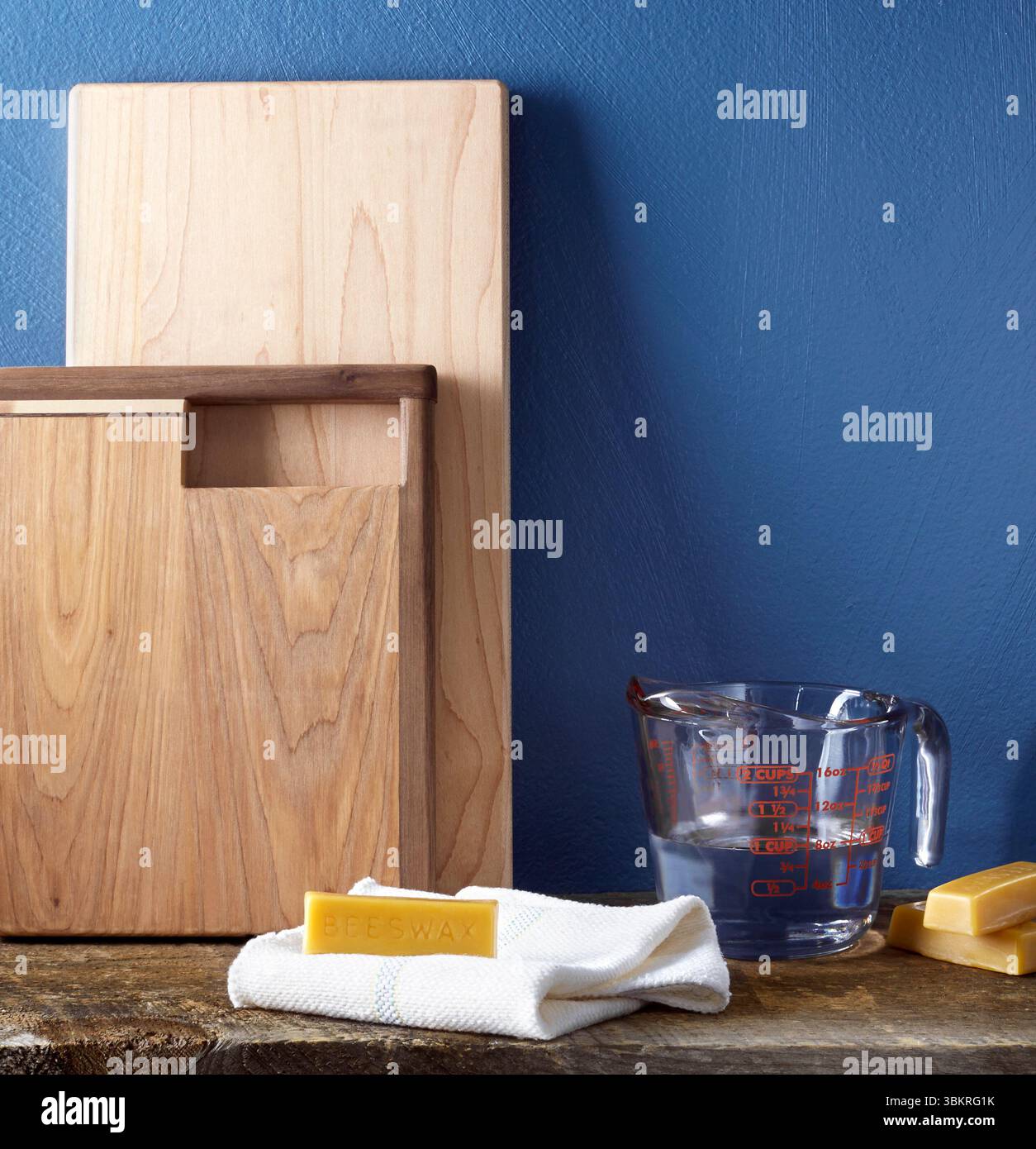 Cutting boards, beeswax bar, water-filled measuring cup on wood Stock ...