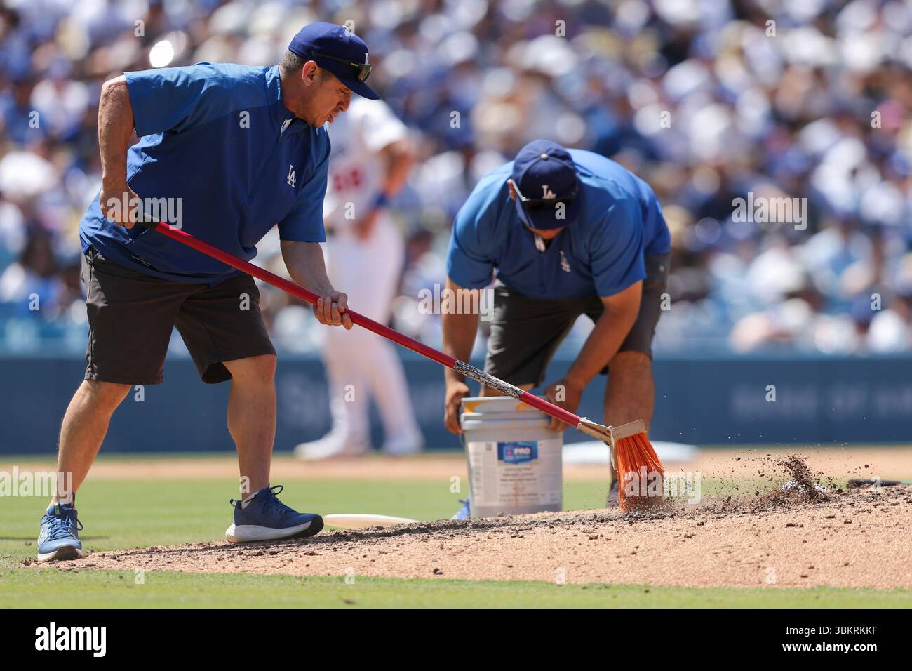 Grounds crew members work on the mound during the sixth inning of a ...