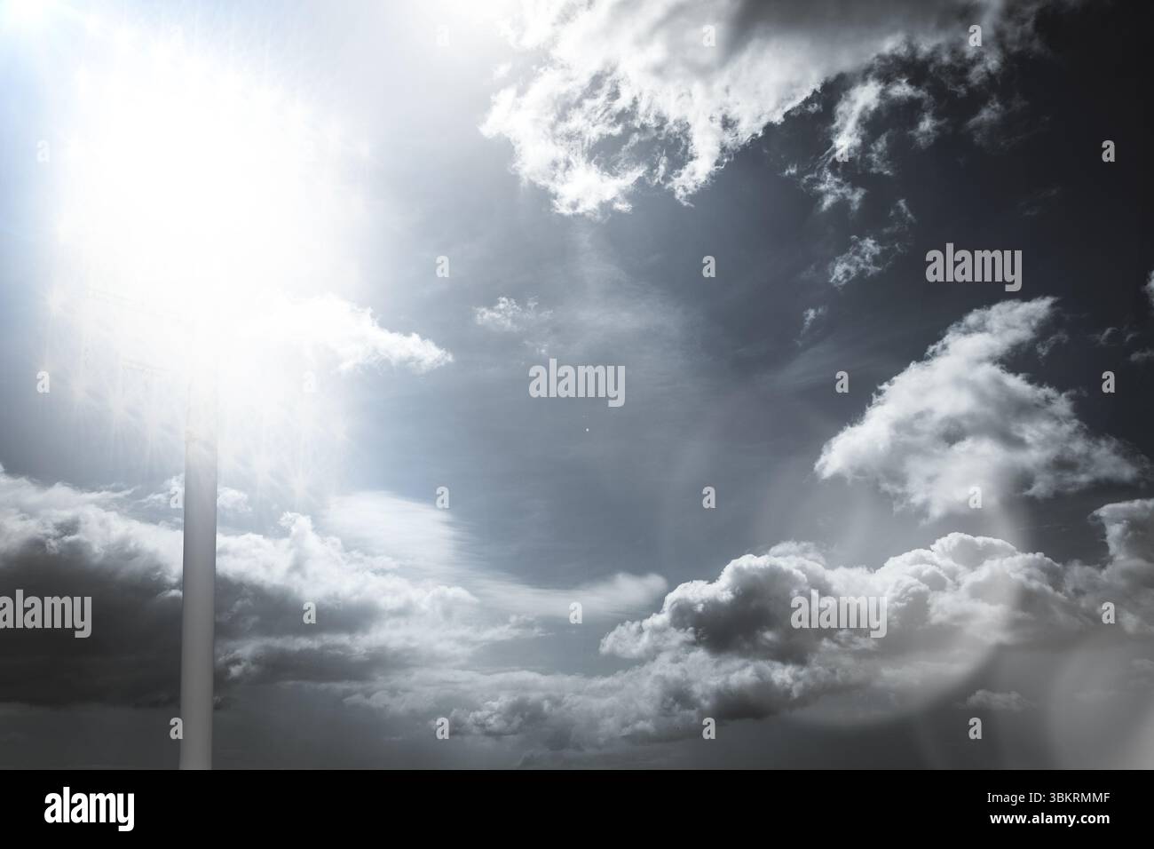 Cloud-filled sky is showcasing sun rays, lens flare and faint pole sign ...
