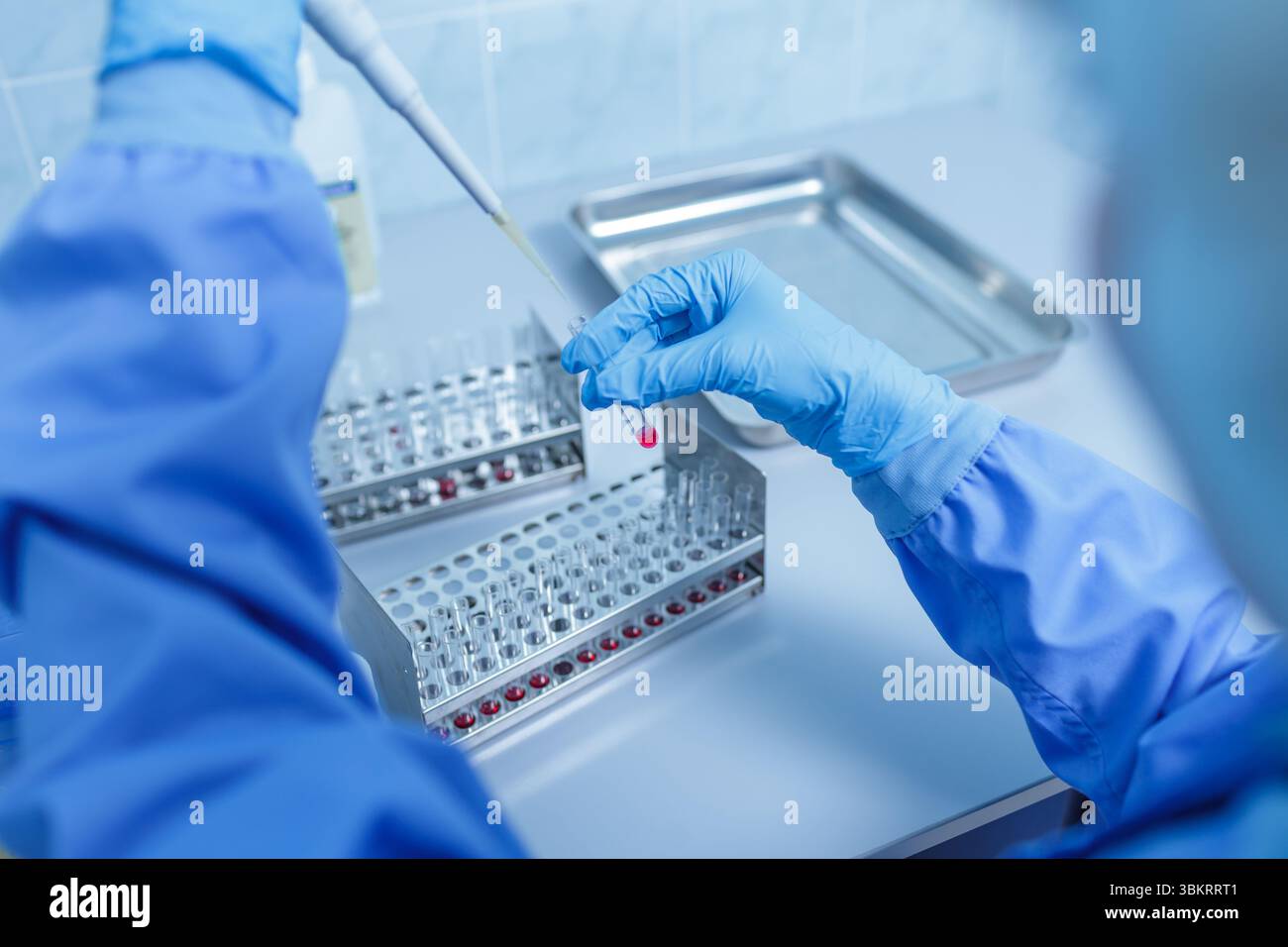 Laboratory technician with pipette transferring liquid sample to test ...