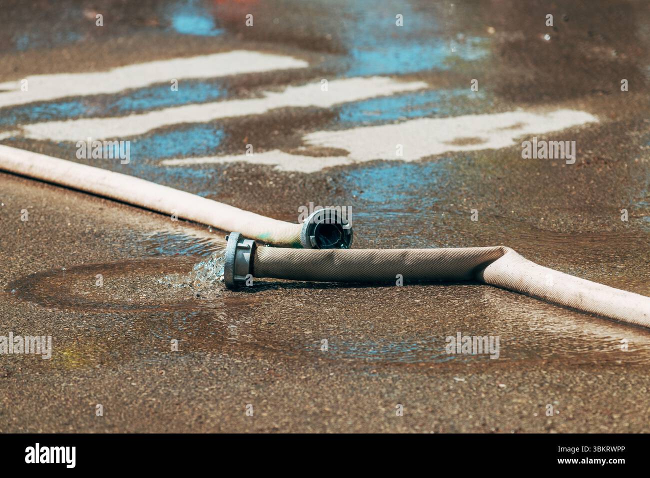 Firefighters water hose leaking on asphalt surface, selective focus ...