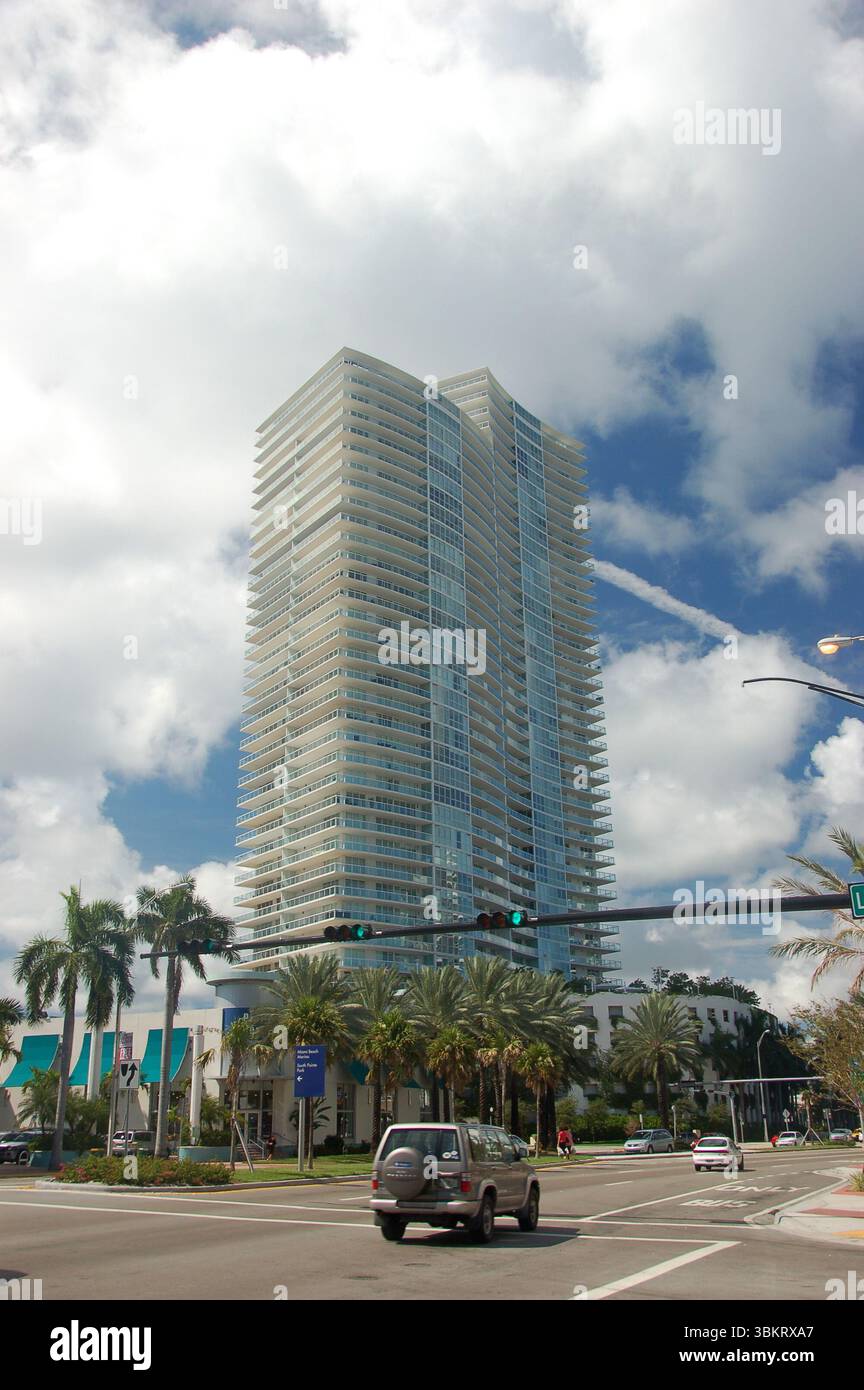 Modern glass skyscraper rises above a palm-lined boulevard in Miami ...