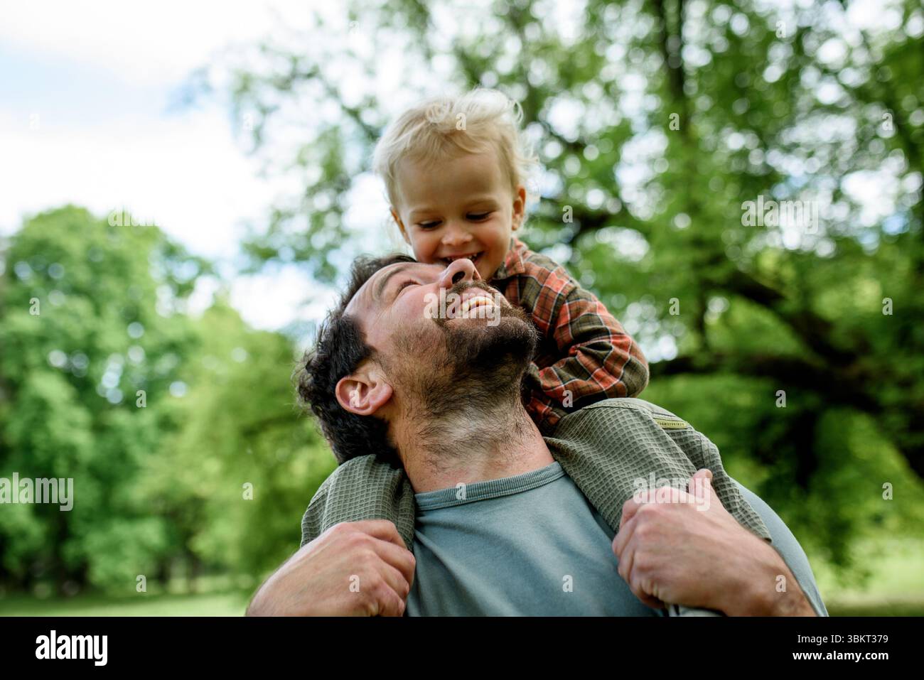 Father carrying his smiling son on shoulders during walk in park Stock ...