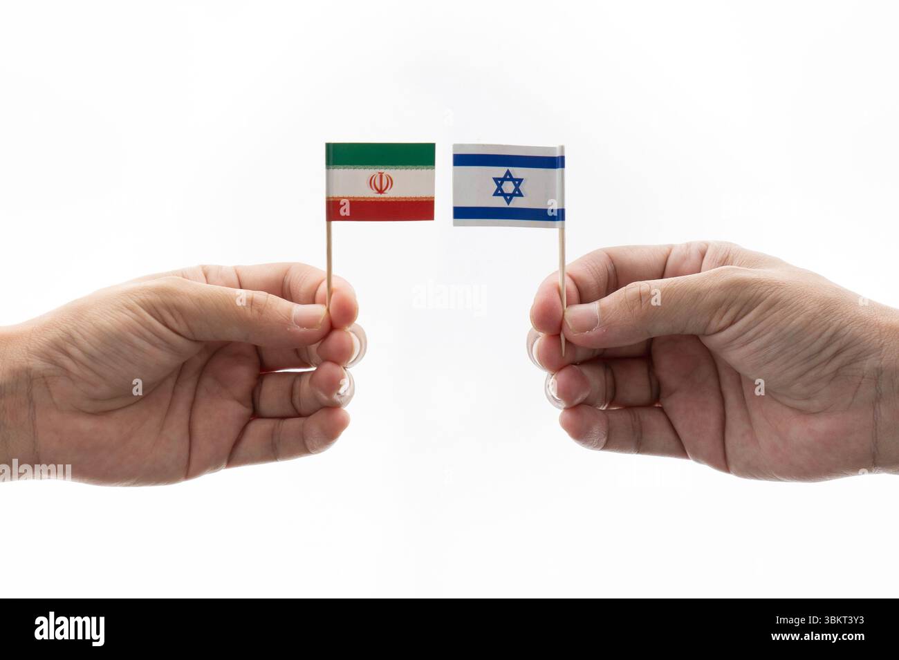 Two hands hold small miniature flags Iran and Israel against a white ...