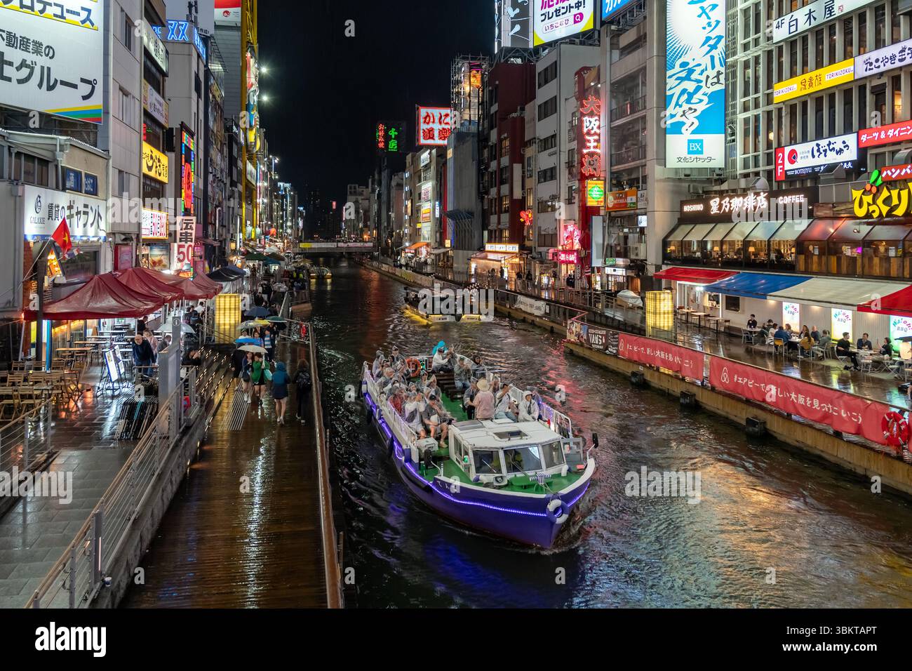 Tourist boats on Dotonbori canal on a wet night. Dotonbori is a ...
