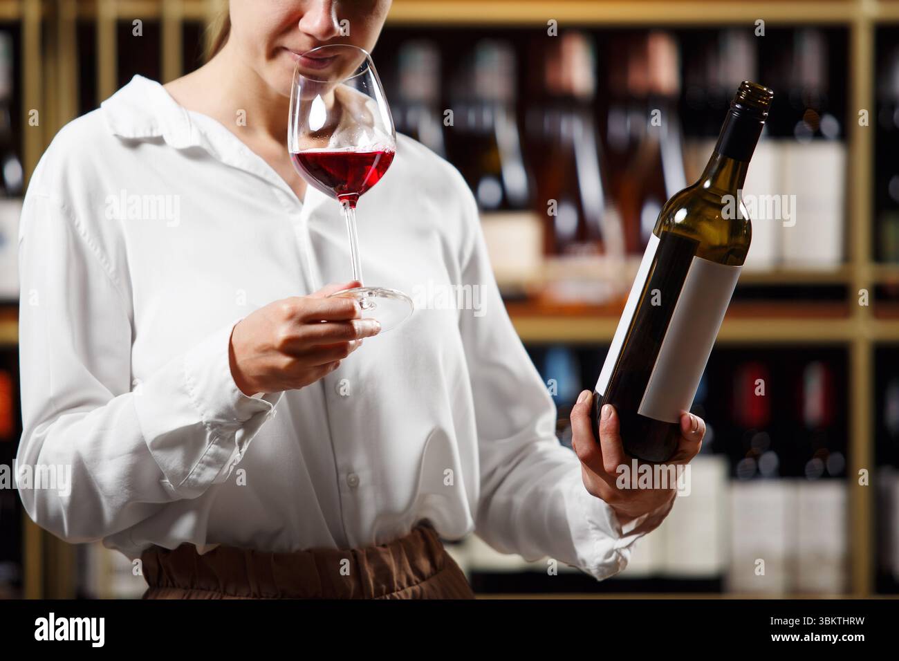 Young beautiful woman sommelier tasting red wine in the wine cellar ...