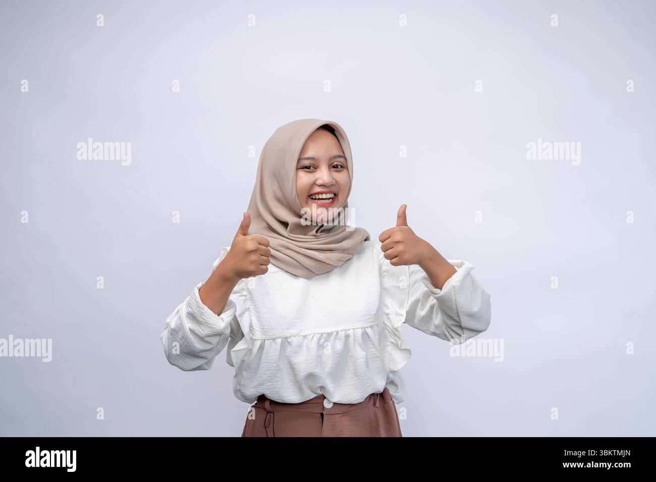 Portrait happy Indonesian woman wearing hijab shows thumb up and ...