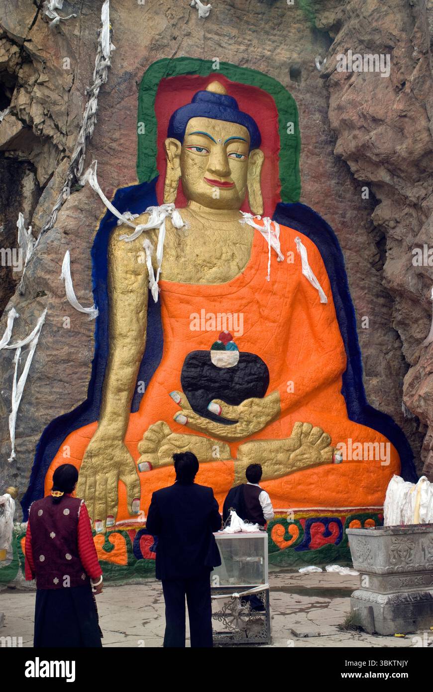 White silk katas, or prayer scarves, adorn the cliff where a Buddha has ...