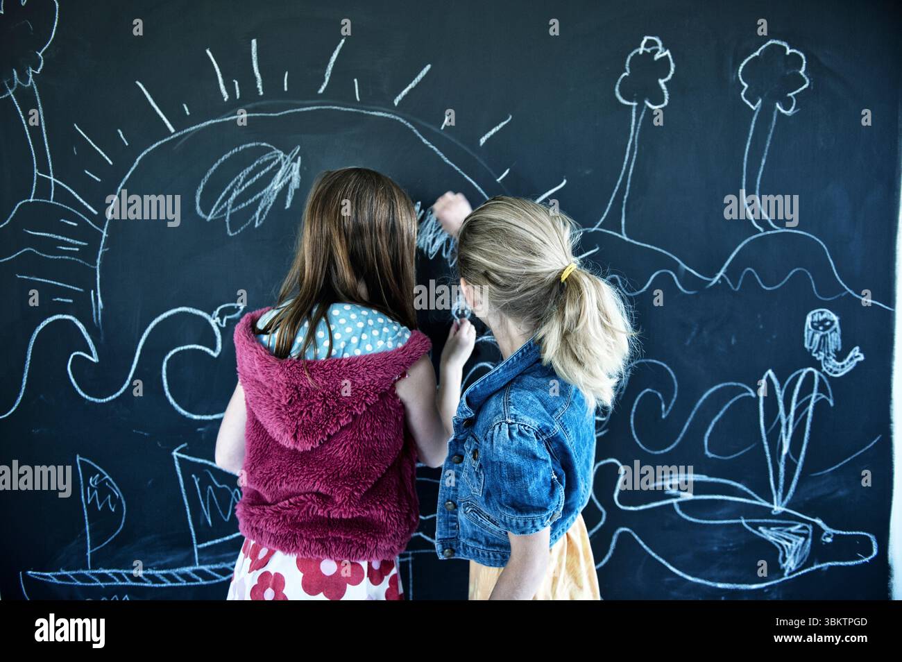 two friends drawing on a blackboard Stock Photo - Alamy