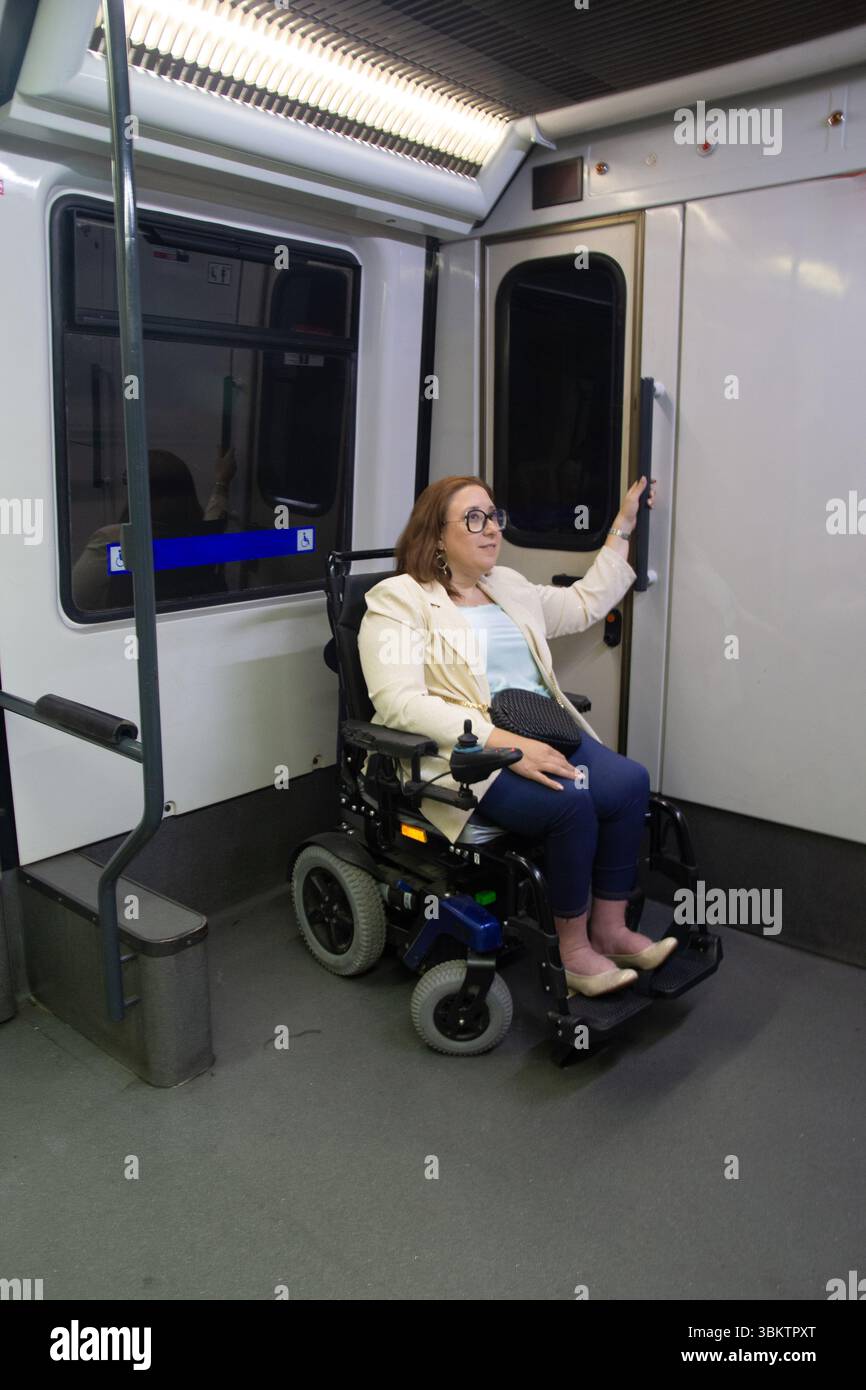 Businesswoman in wheelchair entering subway train through accessible ...