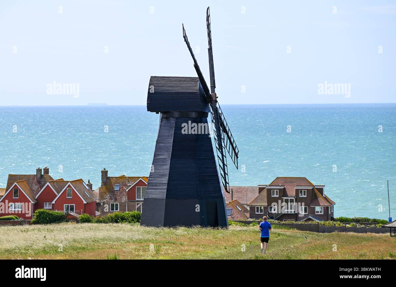 Brighton UK 23rd June 2025 - A runner passes by Rottingdean Windmill ...