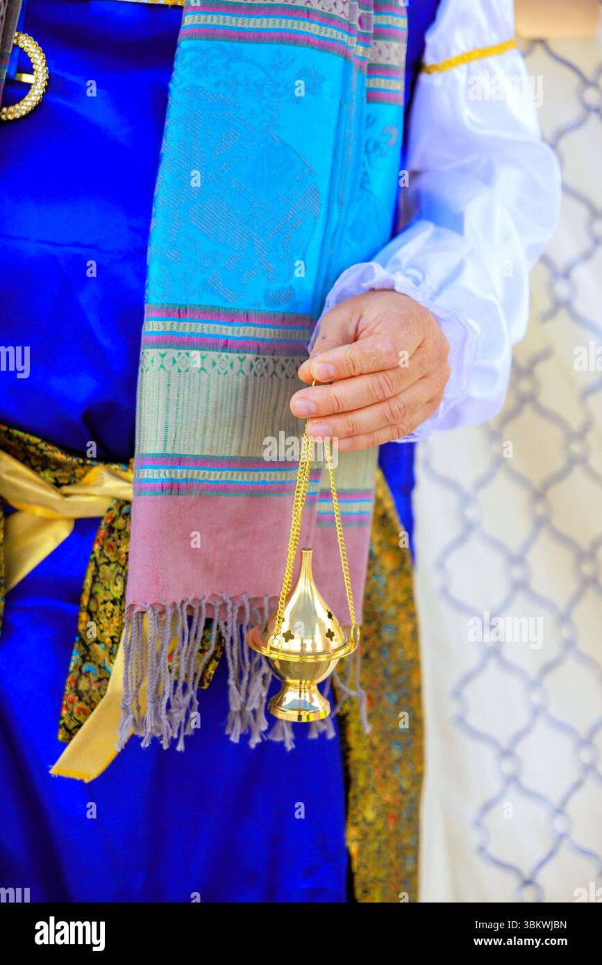 Jewish high priest in vibrant traditional attire holds brass incense ...