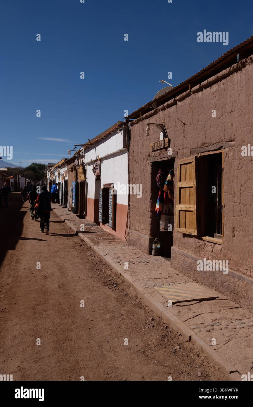 Pedestrians stroll past shops on a dusty street in a traditional town ...