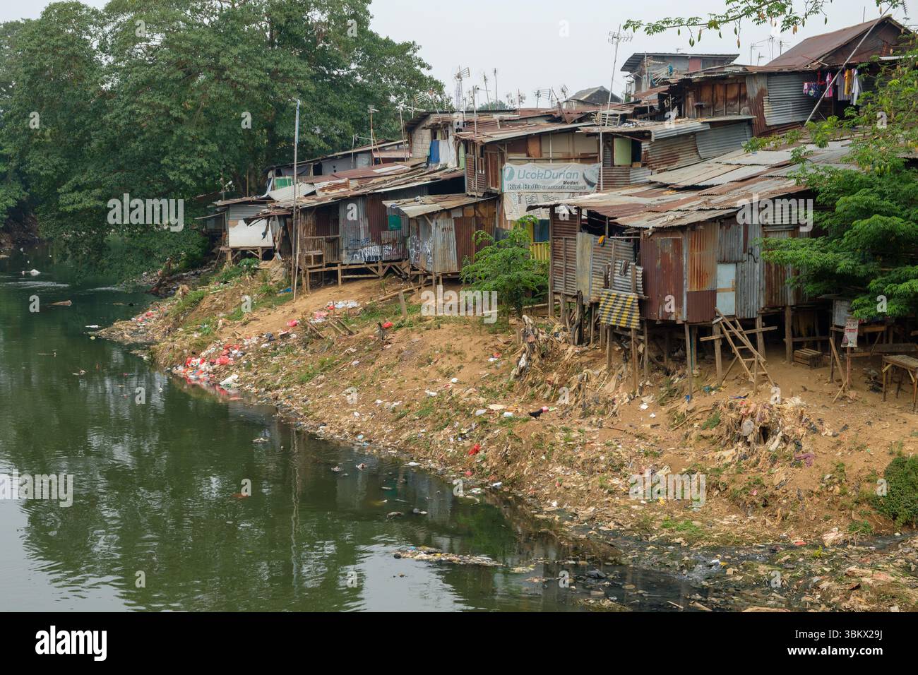 People live in shacks along a trash-filled river, highlighting poverty ...