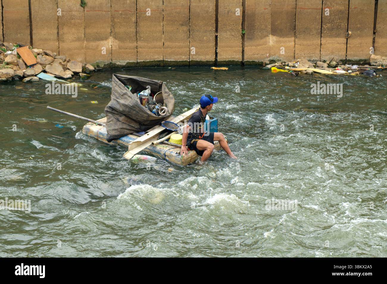 Man on a raft made of trash floats on a polluted river, collecting ...