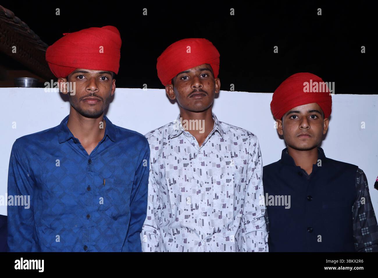 Three young Indian brothers wearing red turban and traditional attire ...