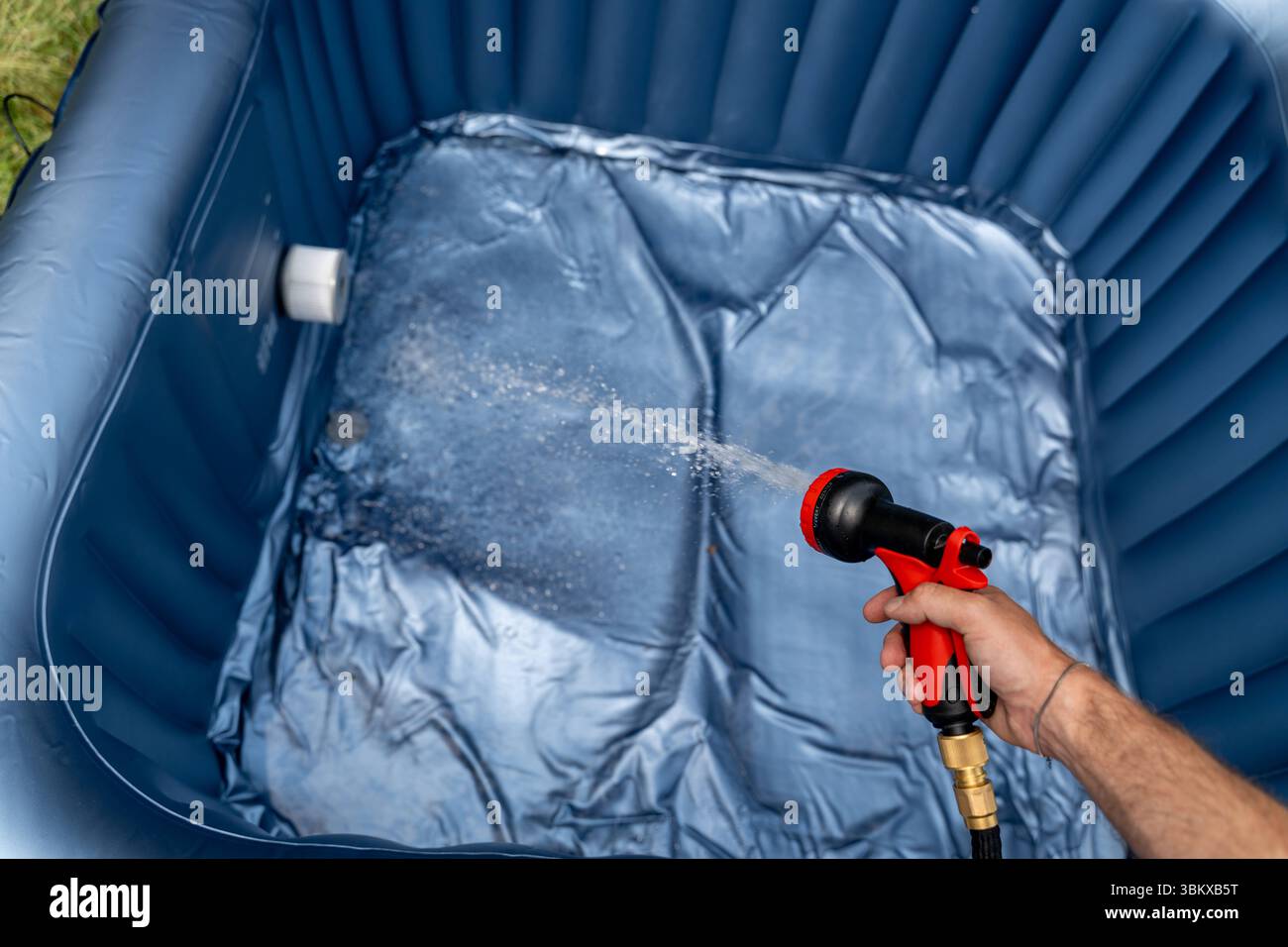 Bavaria, Germany - June 23, 2025: A man fills an inflatable whirlpool ...