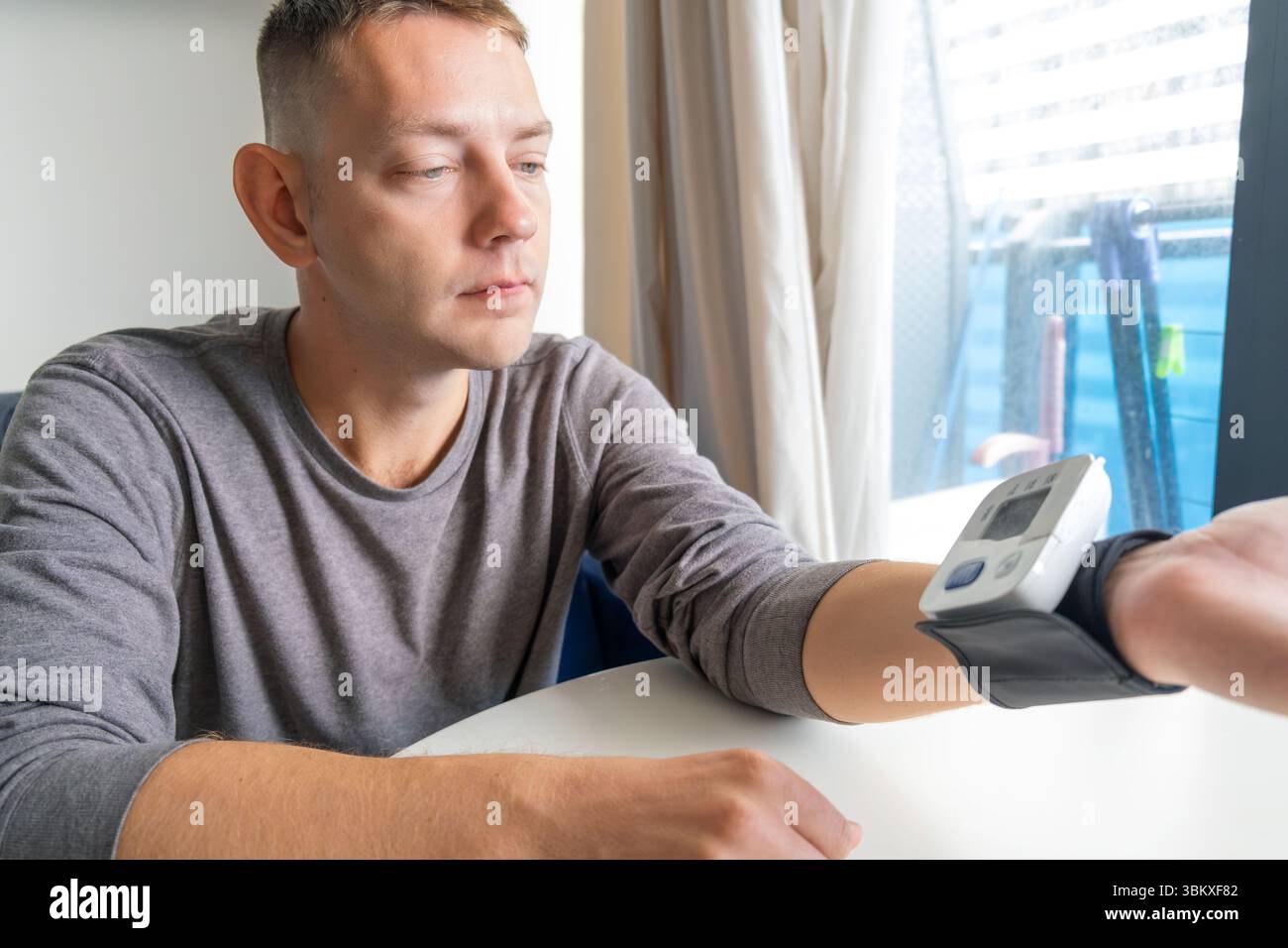 Man using digital wrist blood pressure monitor for measuring blood ...