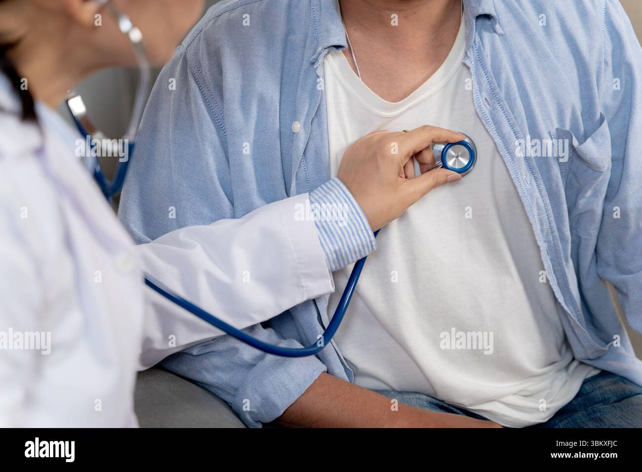 Physician listening to patient’s breath sounds with stethoscope during ...