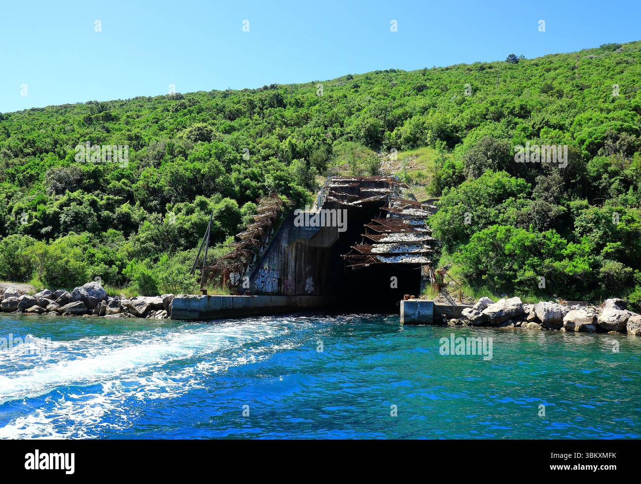 A view of an Abandoned Submarine Bunker with waves from a boat coming ...