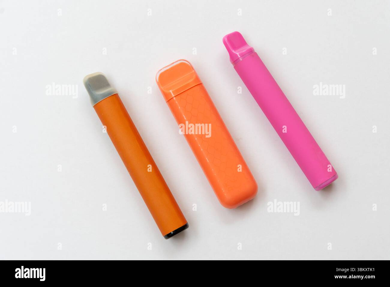 Three disposable electronic cigarettes in bright colors on a white ...