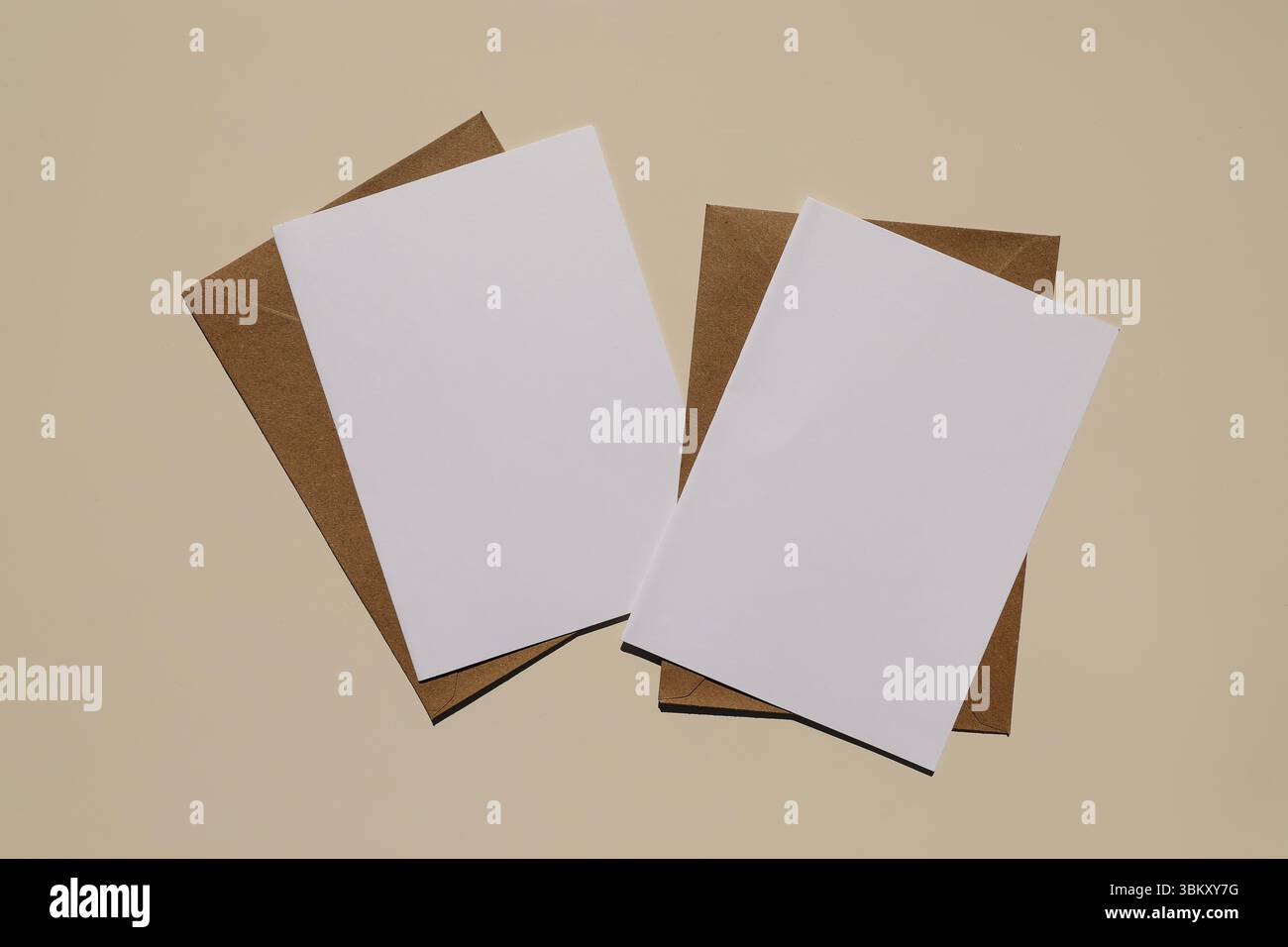 Two blank white cards placed on brown kraft envelopes over neutral ...