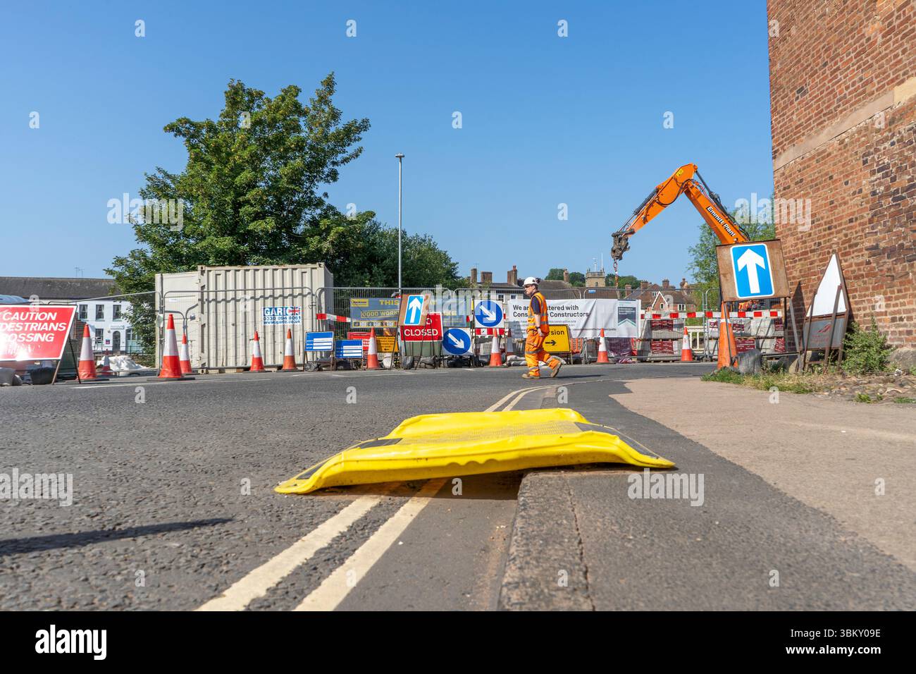 Wheelchair ramp over a curb on a road with roadworks, crane, workman ...
