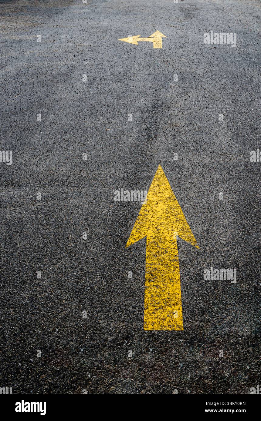 Two Yellow arrows on pavement pointing ahead and one pointing ahead and ...