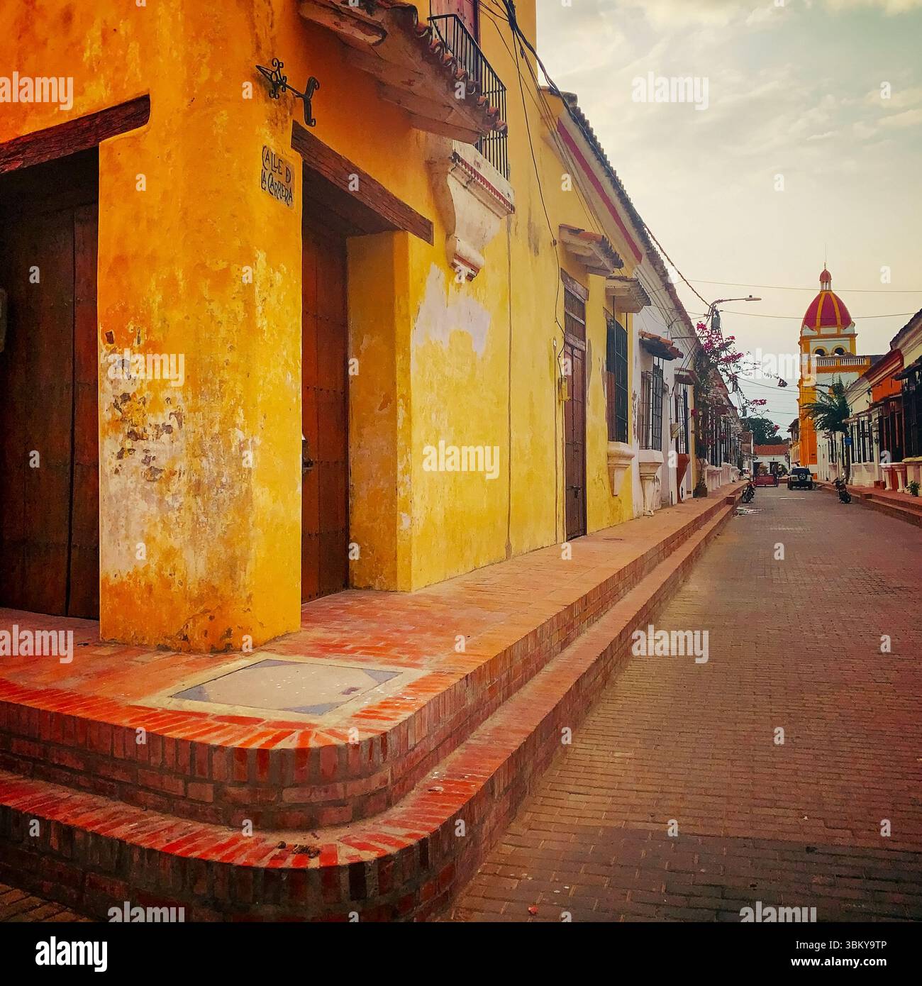 A view of a clay brick pathway, lined with Spanish colonial houses ...
