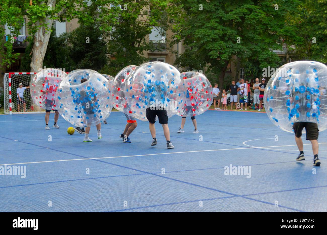 Energetic bubble soccer game on blue court with players in inflatable ...
