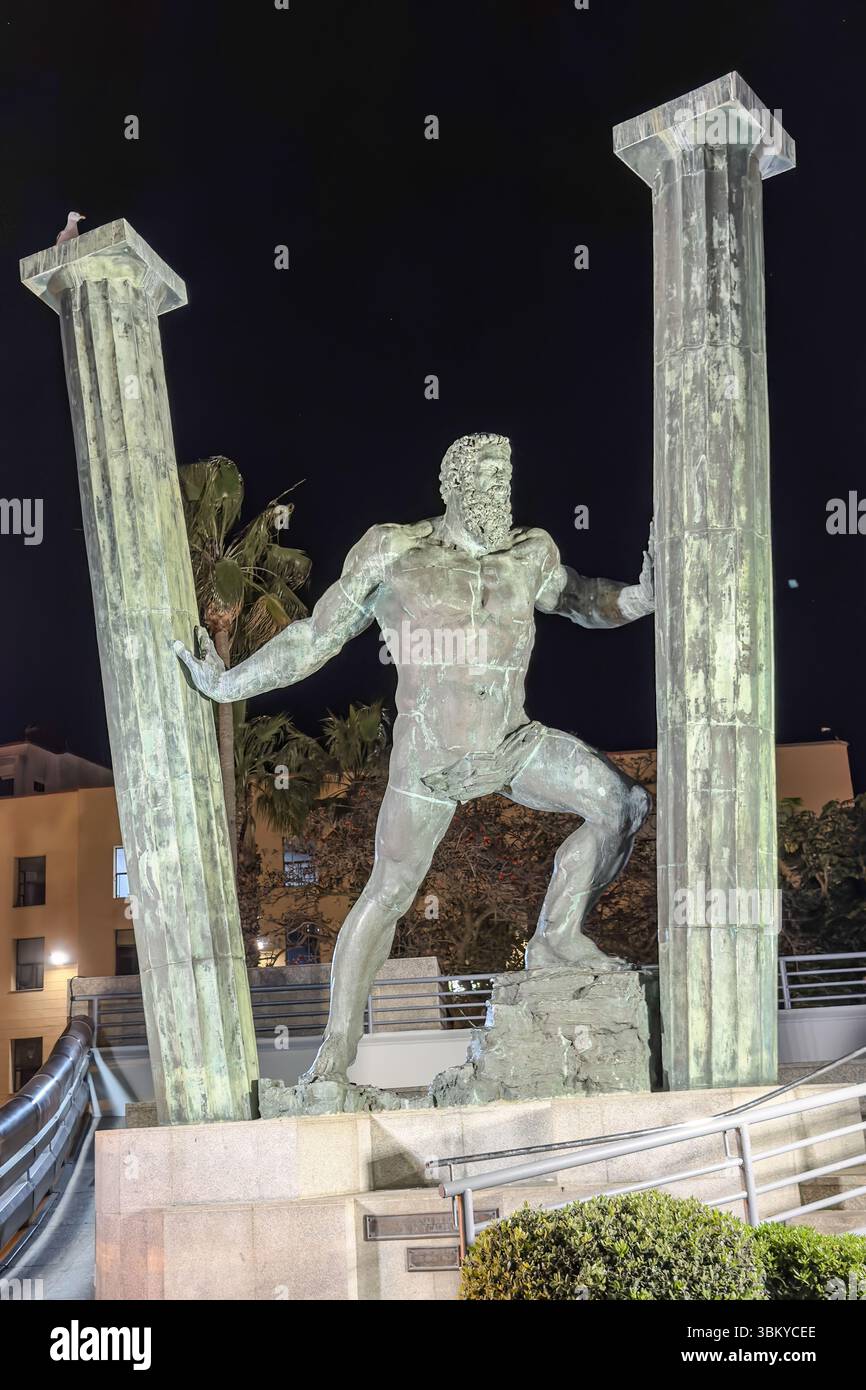 Bronze statue of Hercules holding the Pillars of Hercules at night in ...