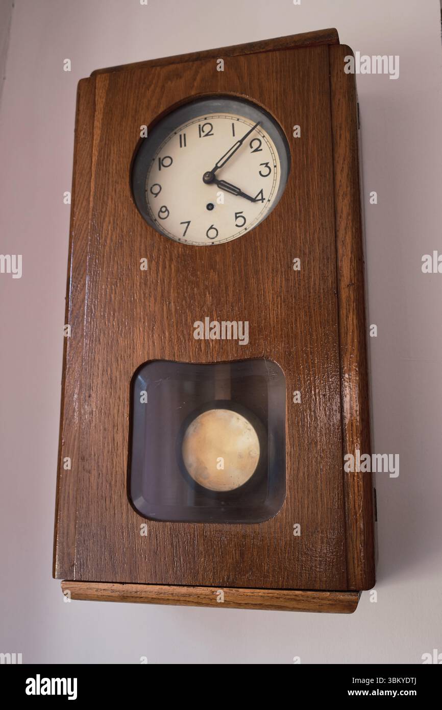 Vintage wooden wall clock with pendulum, showing time. Rustic detail in ...