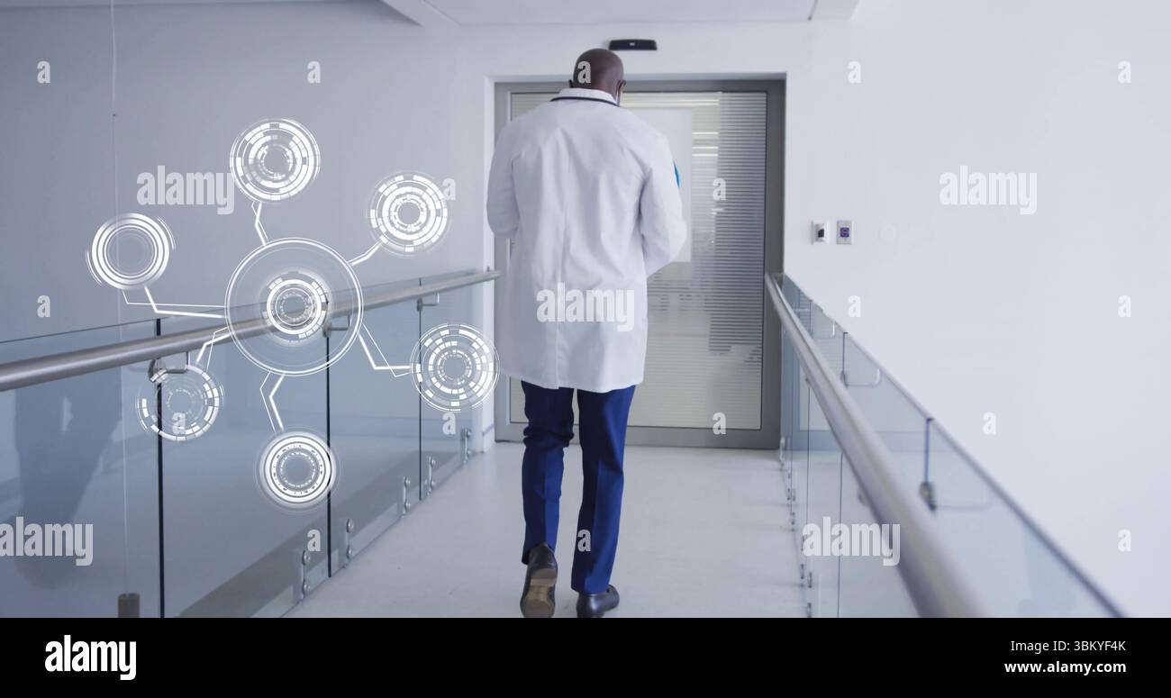 Walking doctor wearing lab coat down hospital hallway, with glass ...