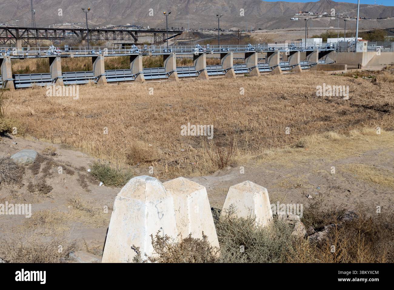 A wide, dry riverbed stretches across the frame, leading towards a ...