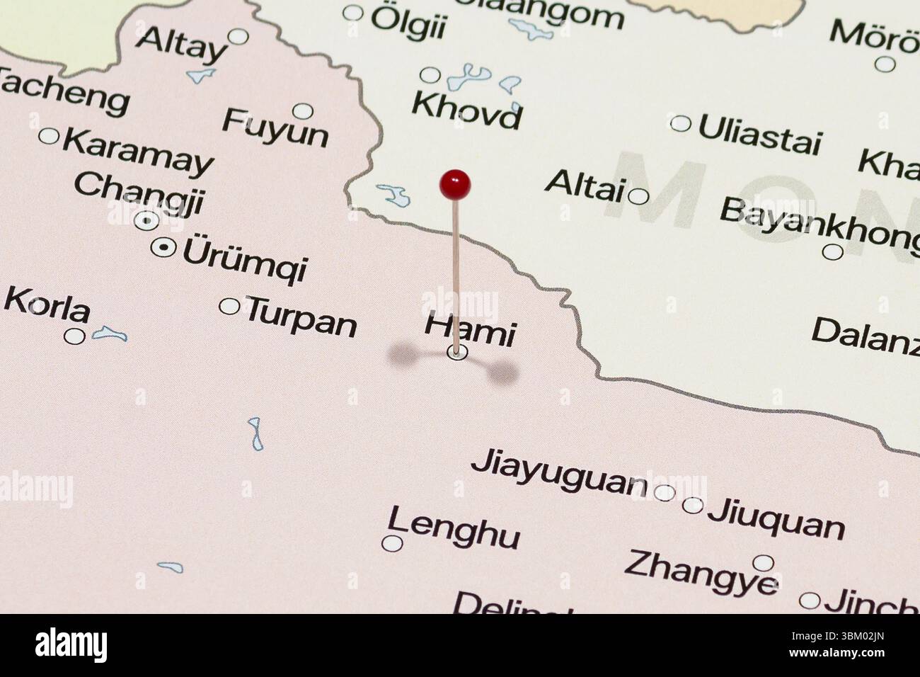 macro photo of a red pin needle into Hami city of China political map ...
