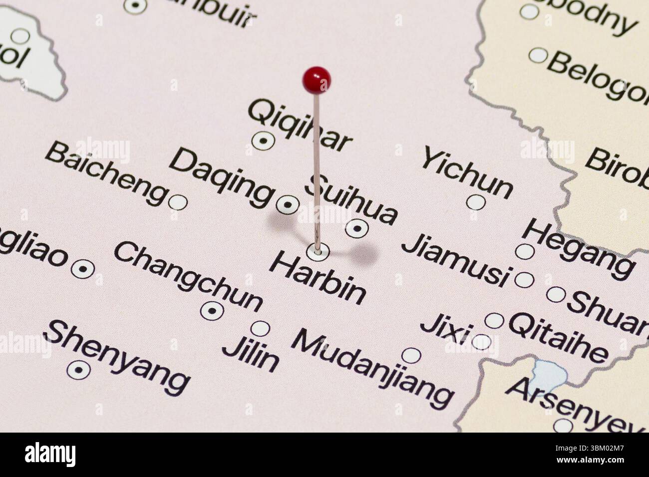 macro photo of a red pin needle into Harbin city of China political map ...
