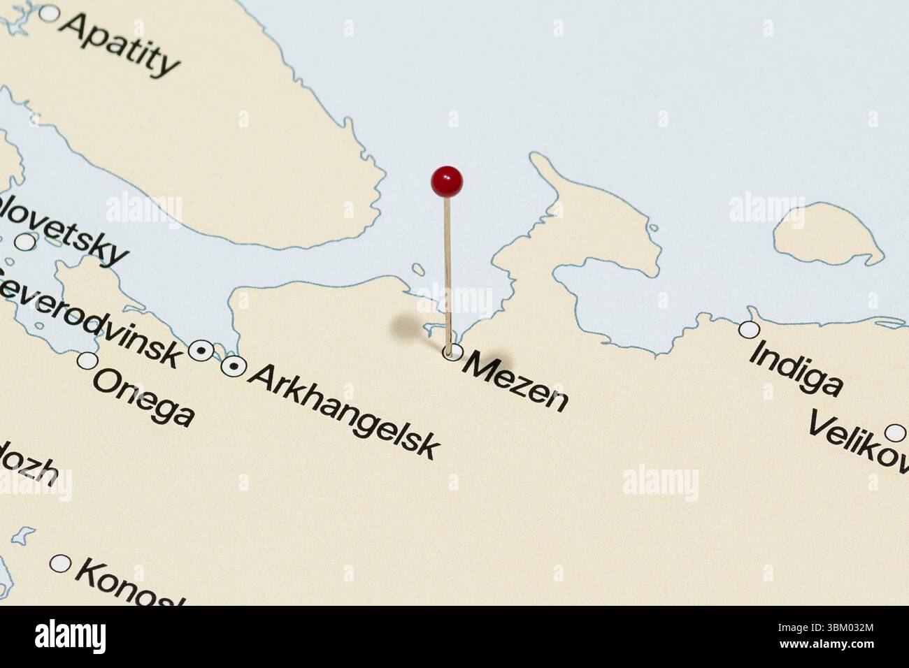 macro photo of a red pin needle into Mezen city of Russia political map ...