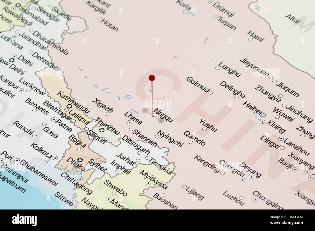 macro photo of a red pin needle into Nagqu city of China political map ...
