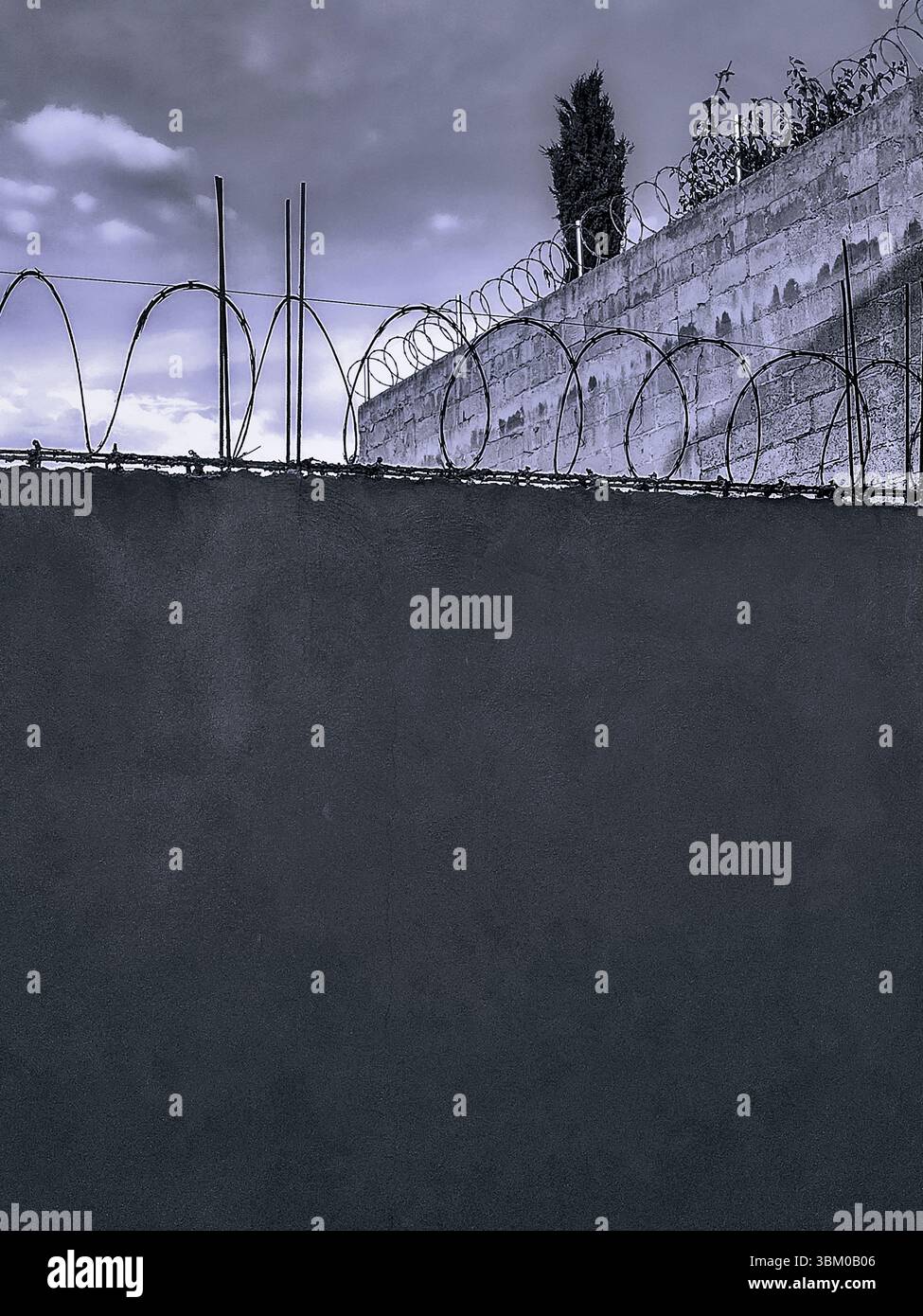 Ordinary life in Mexico behind a high fence with barbed wire. Black and ...